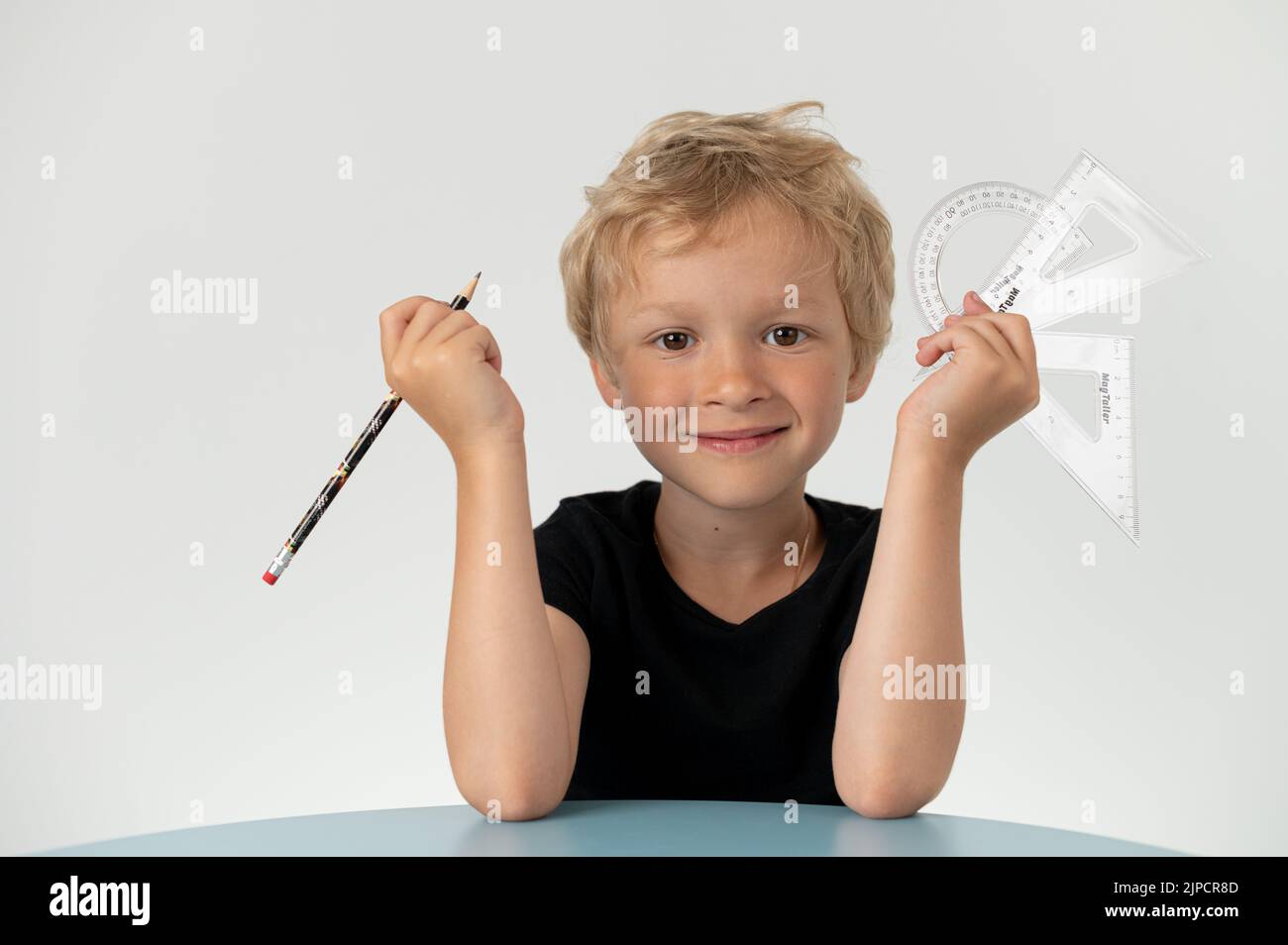 Boy with a pencil sitting at a table, school education Stock Photo - Alamy