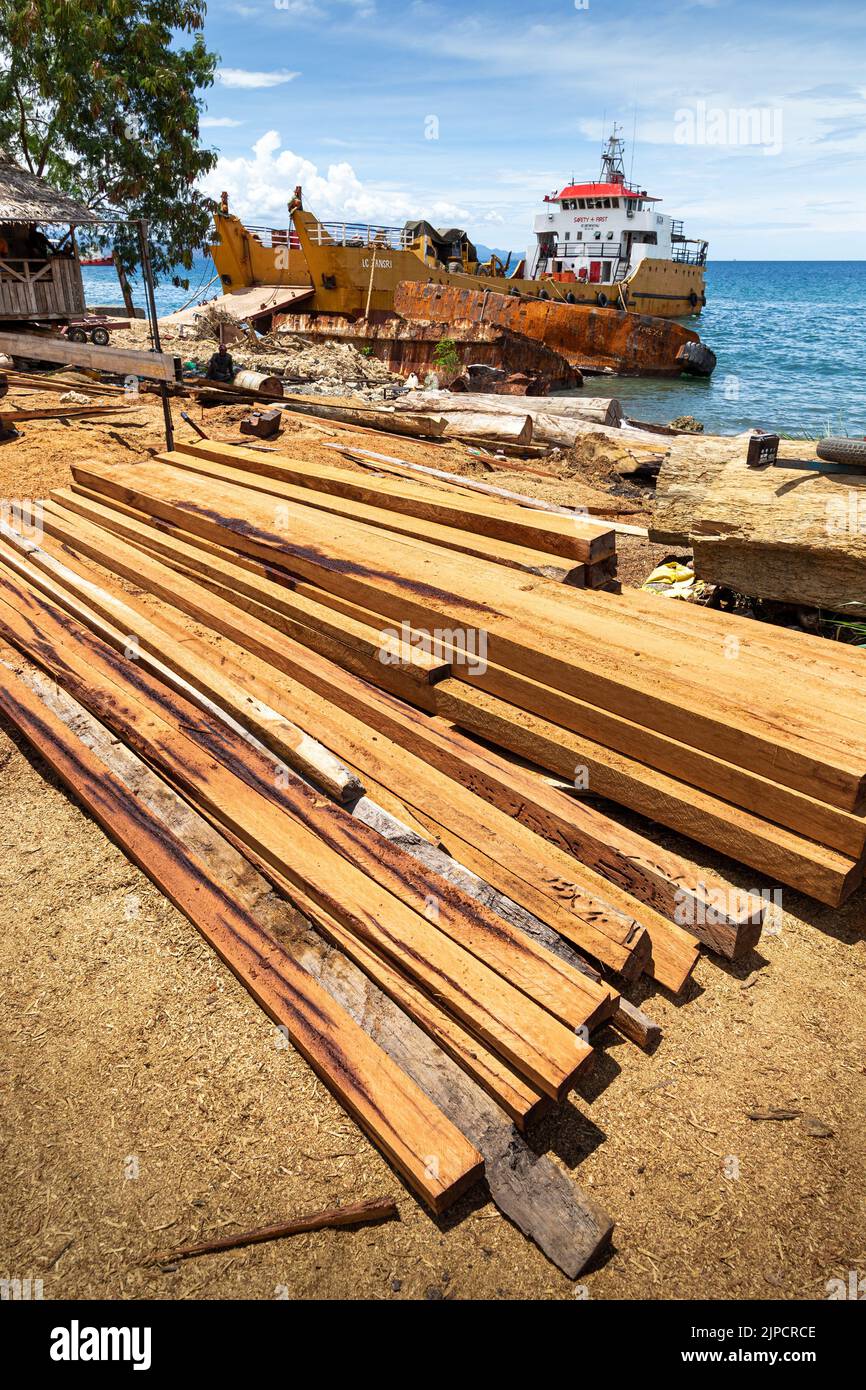 Piles of freshly milled timber waiting to be loaded onto a boat in an ...