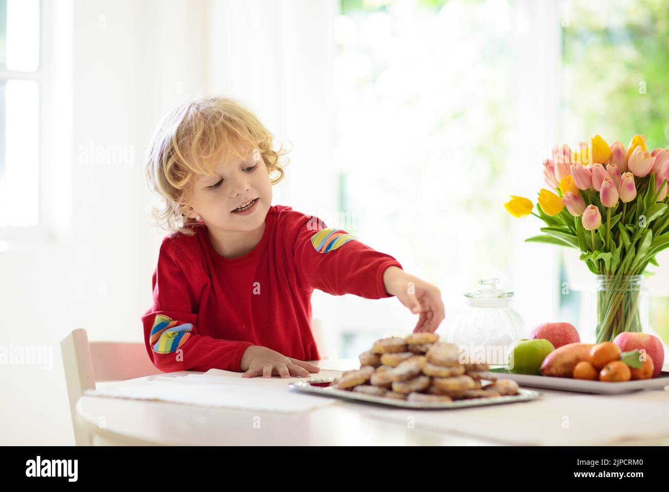 Child eating breakfast. Kid drinking milk with fresh homemade cookies ...