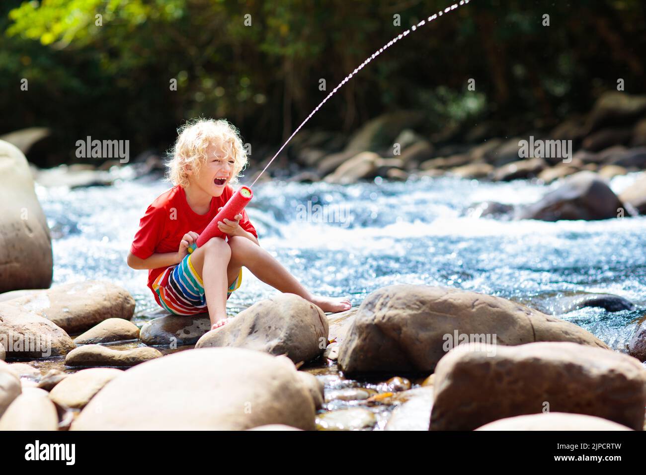 Children hiking in Alps mountains crossing river. Kids play in water at ...