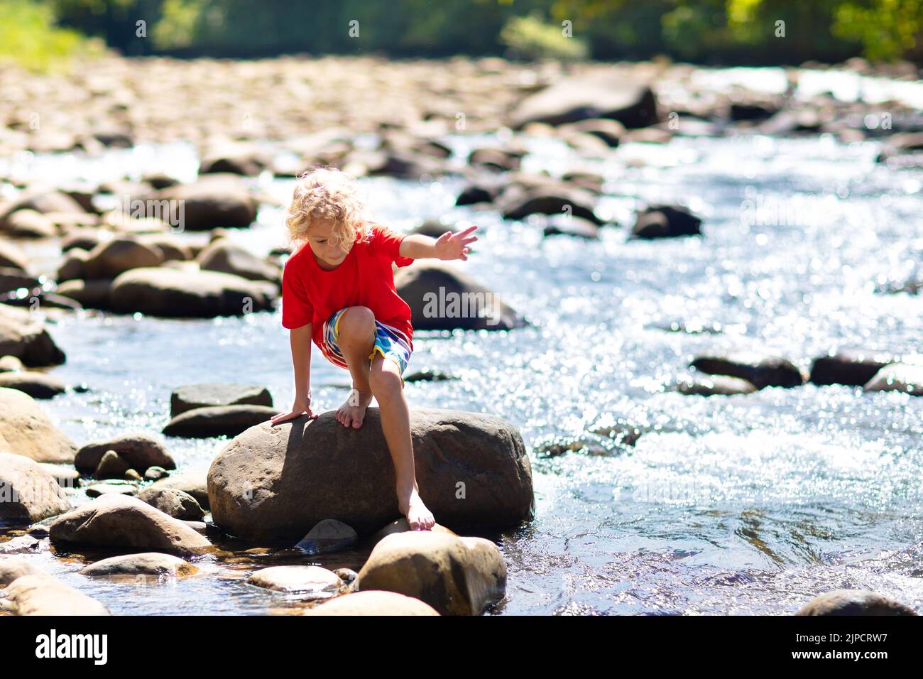 Children hiking in Alps mountains crossing river. Kids play in water at ...