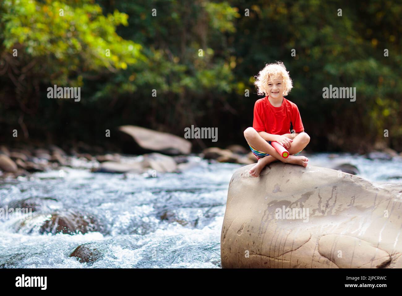 Children hiking in Alps mountains crossing river. Kids play in water at ...