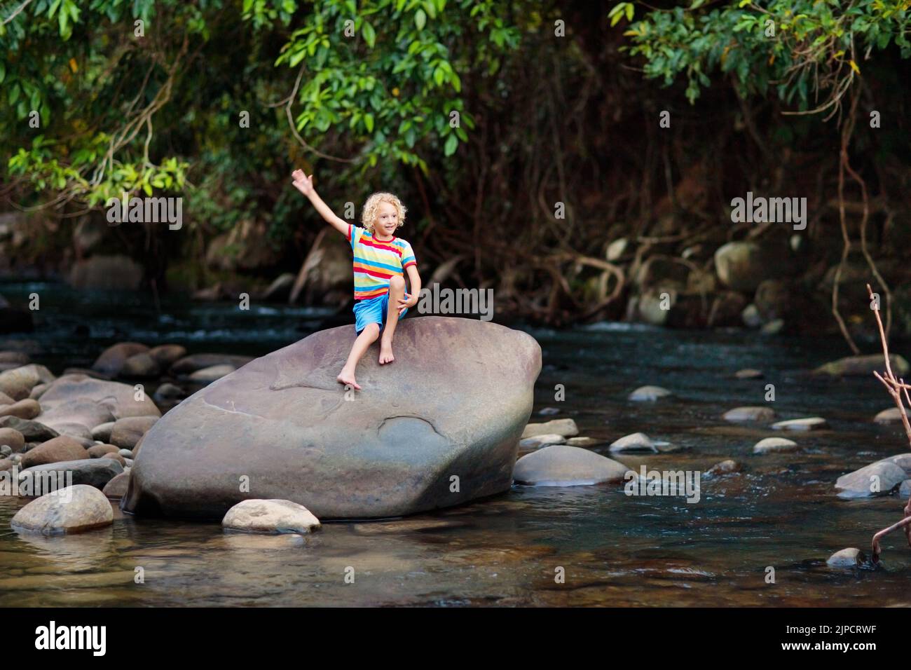 Children hiking in Alps mountains crossing river. Kids play in water at ...