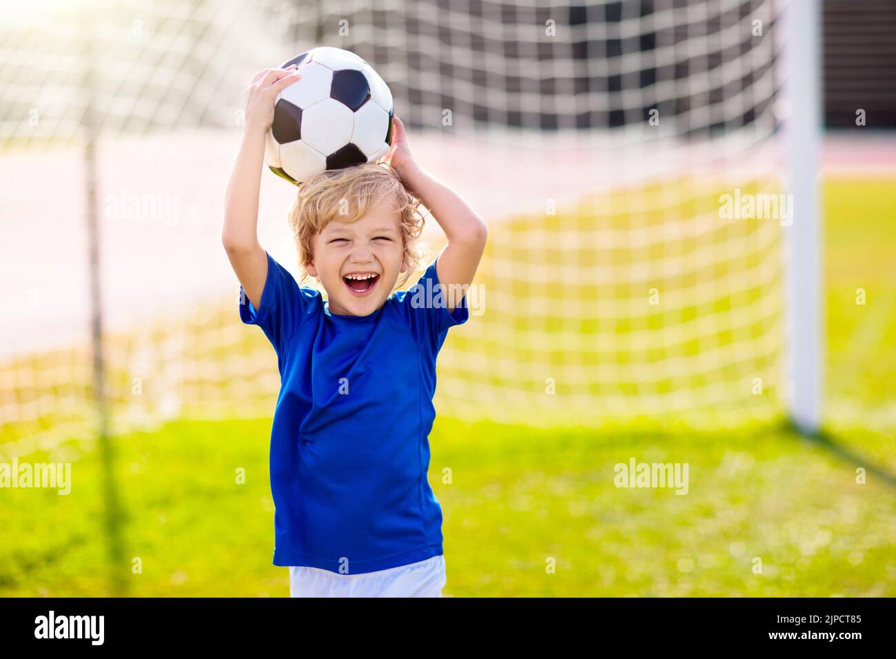 Kids play football on outdoor stadium field. Children score a goal ...
