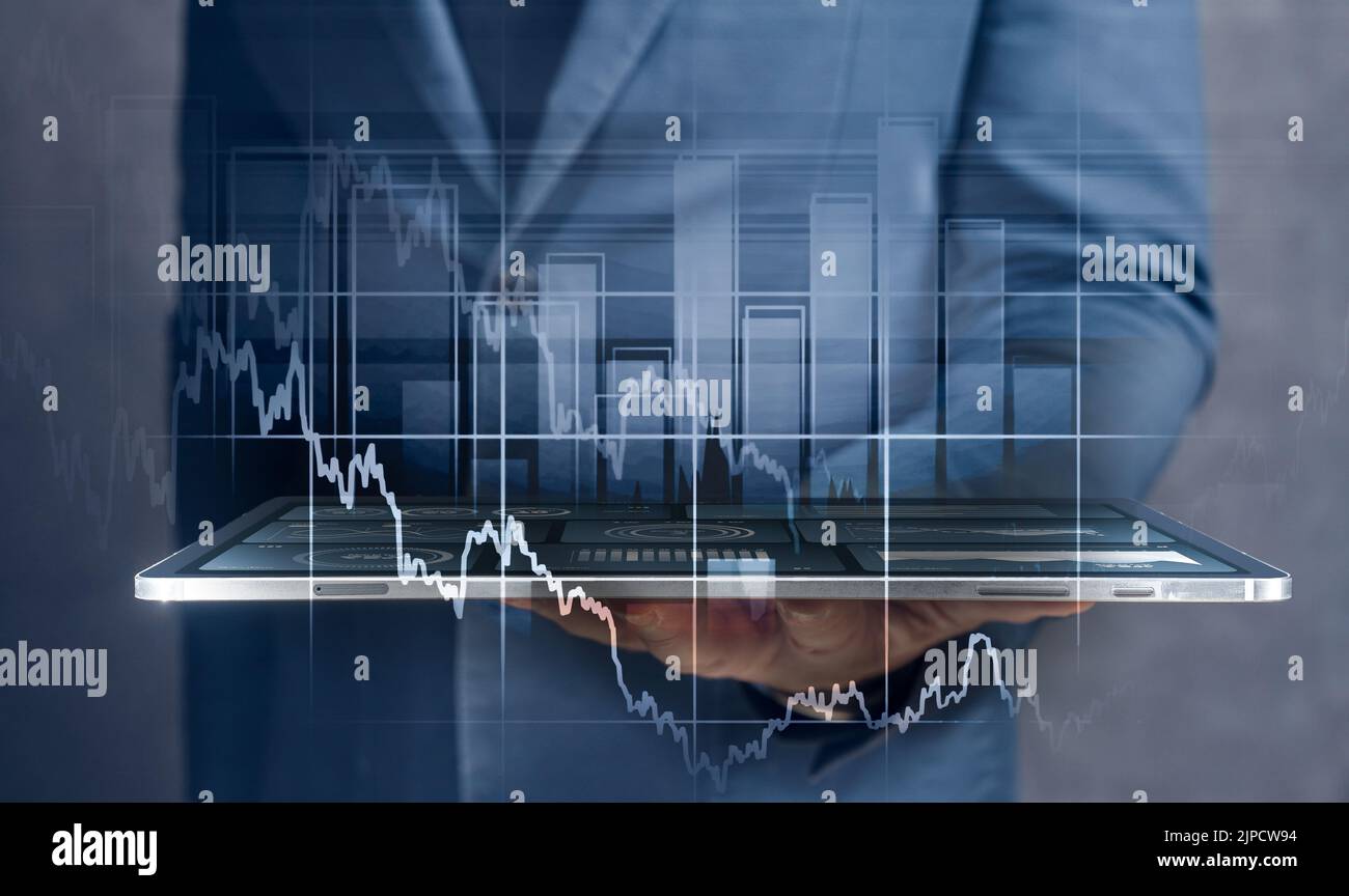 Businessman using tablet and laptop analyzing sales data and economic growth graph chart ...