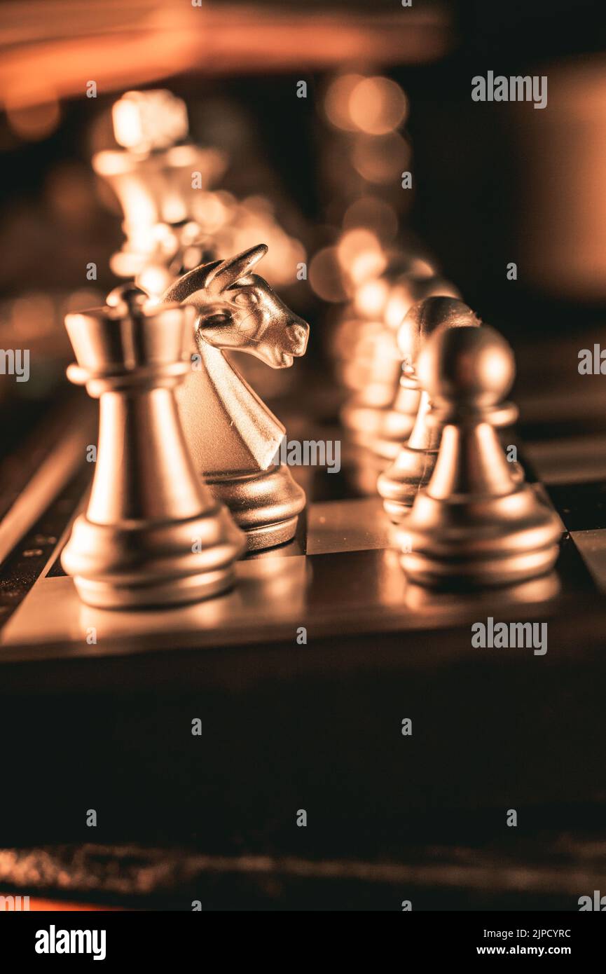 A vertical closeup shot of gold metallic organized chess pieces on a ...
