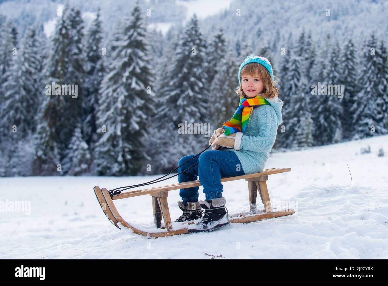 Funny boy having fun with a sleigh in winter forest woods. Cute ...