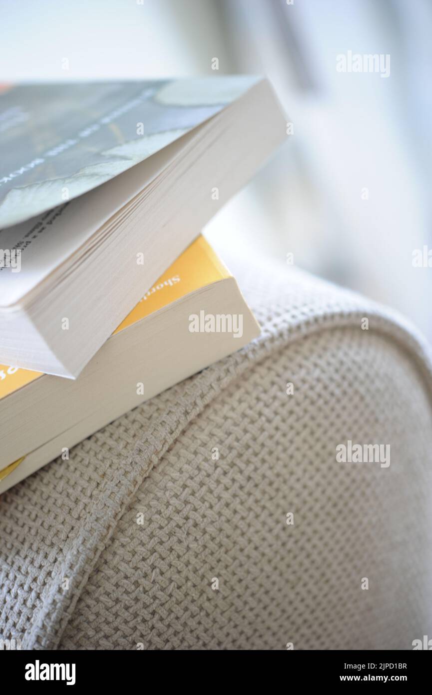 Paperback Books on the arm of a blue stripped chair Stock Photo - Alamy