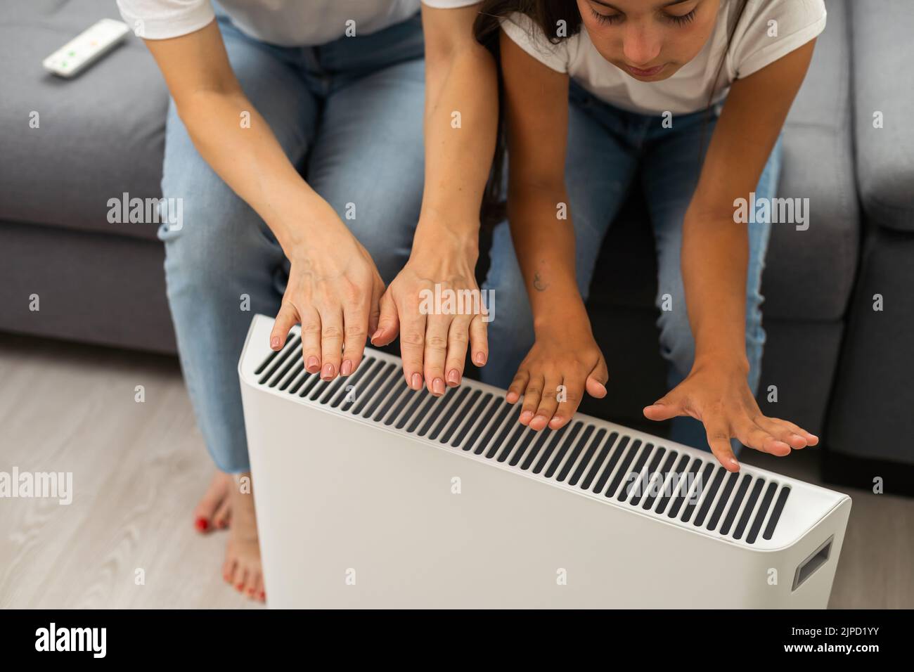 Cold home, freezing family, mother and daughter Sitting Near Heater ...