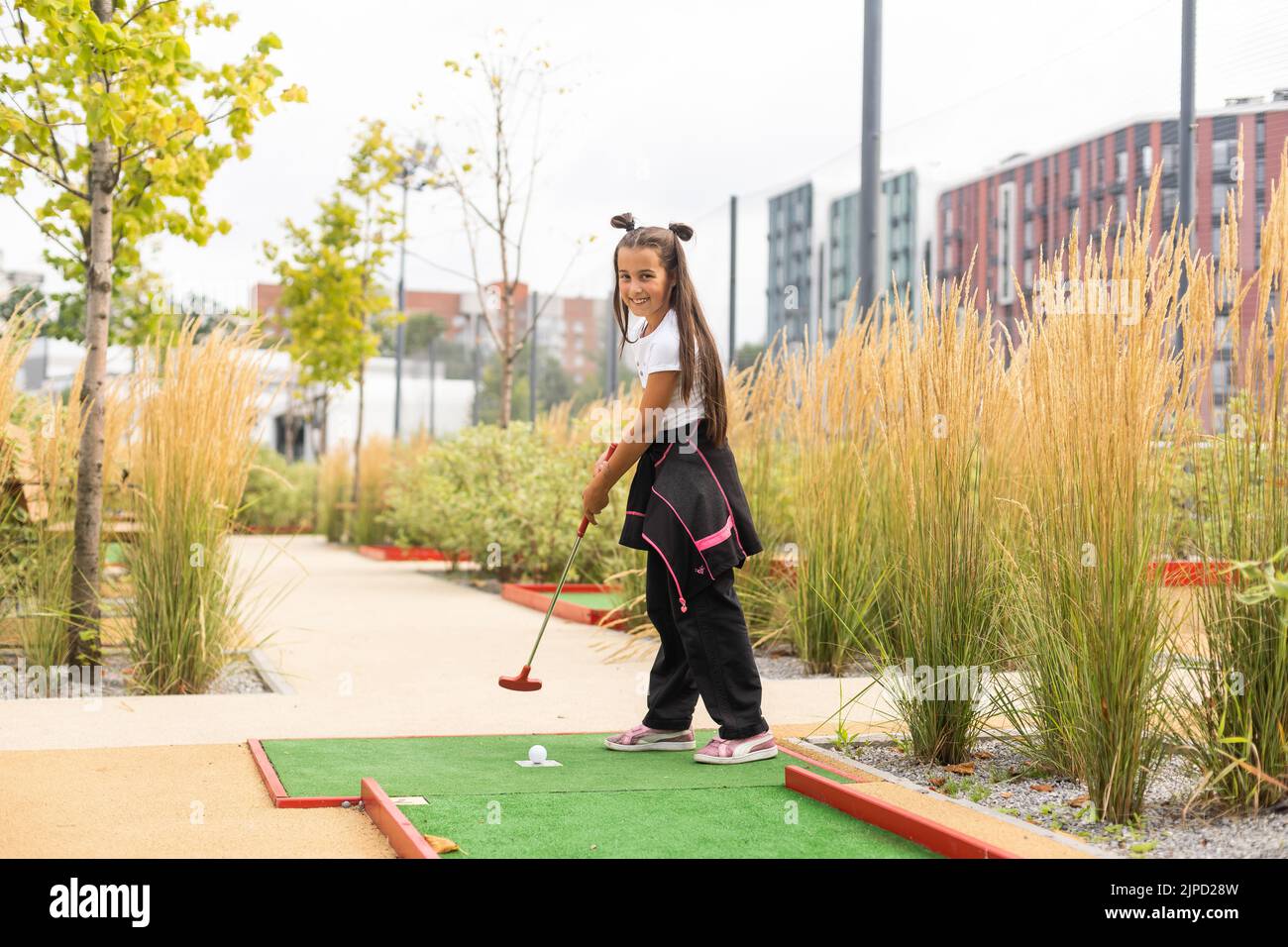Cute preschool girl playing mini golf with family. Happy toddler child ...