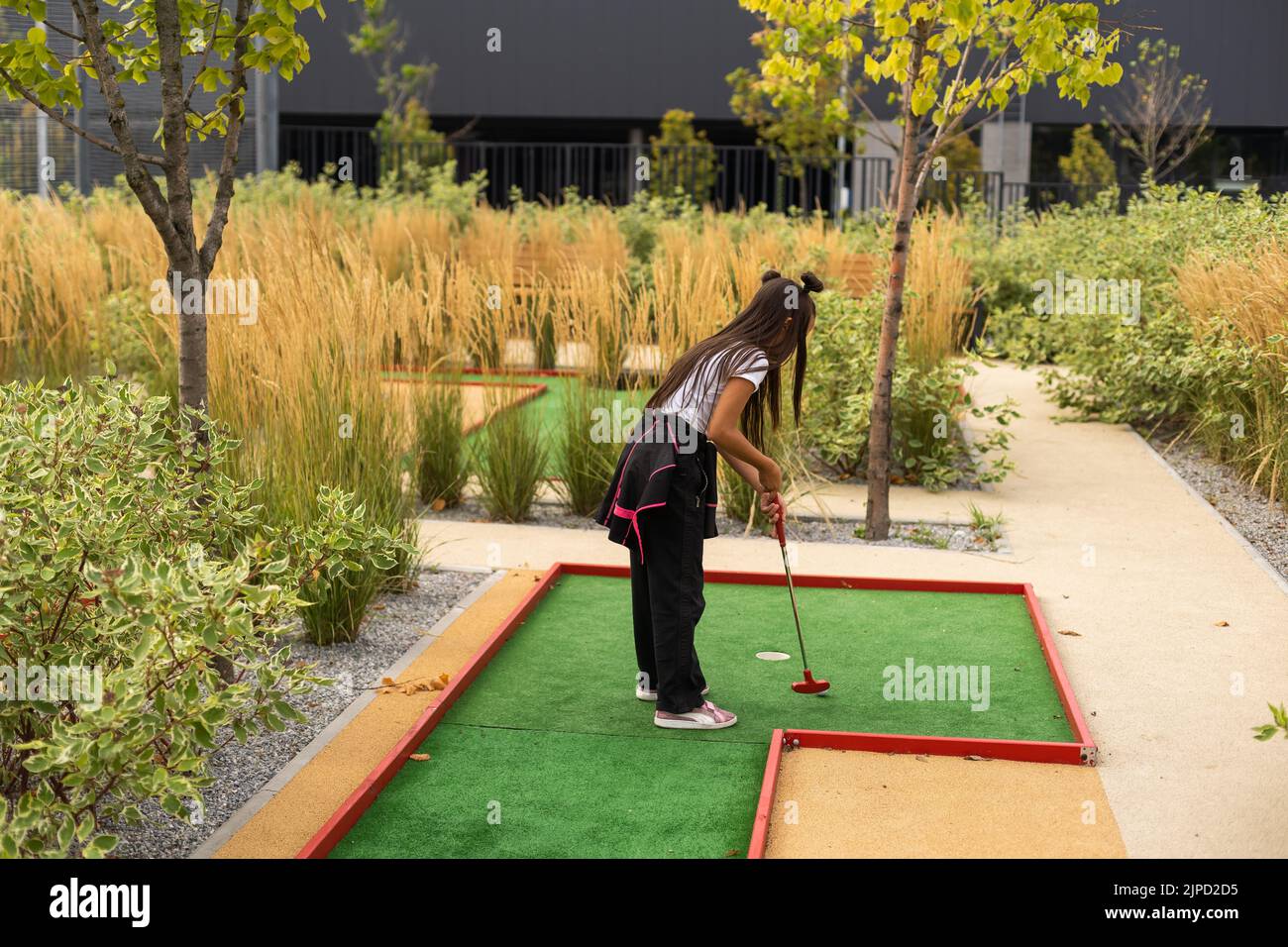 Cute preschool girl playing mini golf with family. Happy toddler child ...