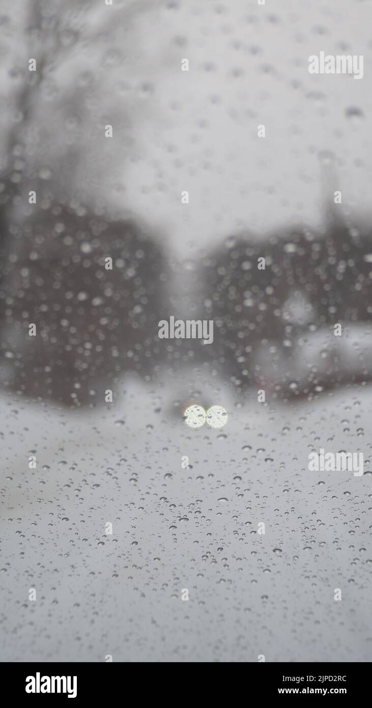 A vertical shot of raindrops on glass surface on blur background Stock ...