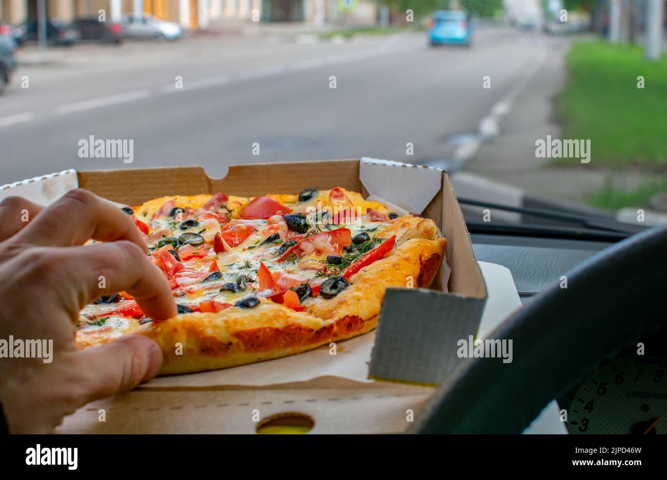 pizza in a cardboard box lies on a panel inside the car against the ...