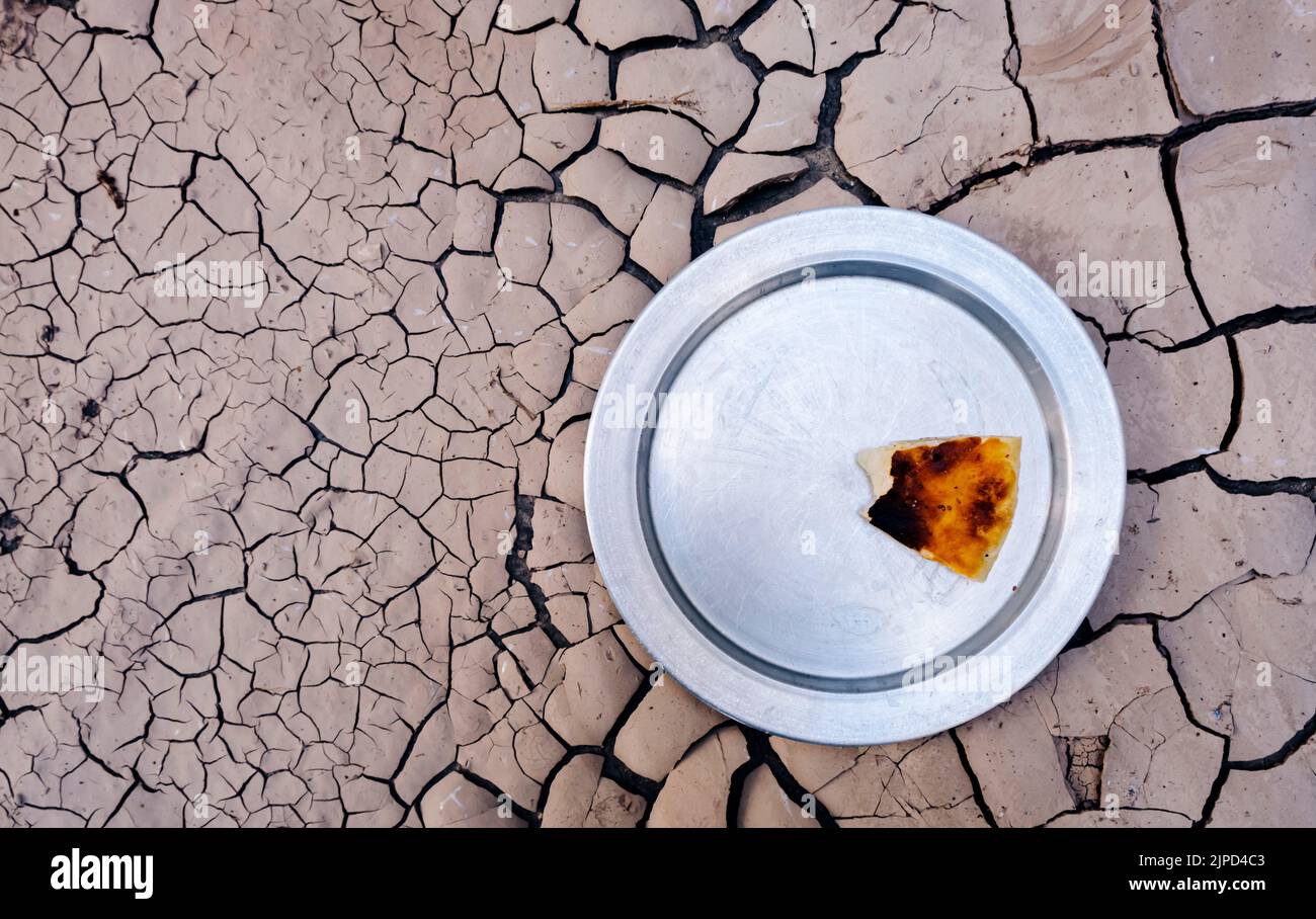 Iron plate and piece of bread on dry soil Stock Photo - Alamy