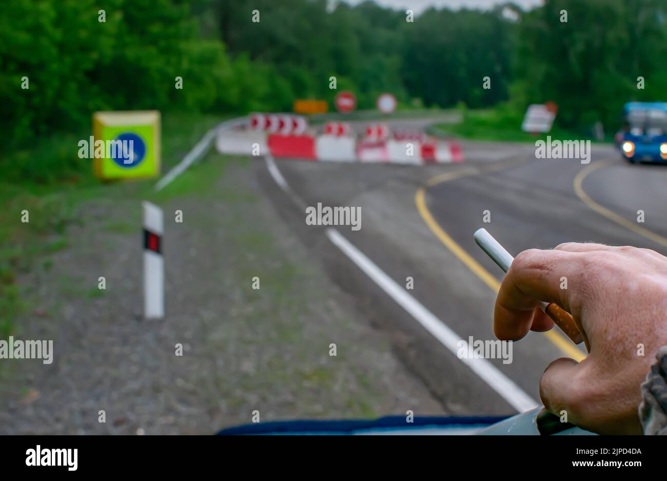 a cigarette in the hand of a person who stopped at a car in front of a ...