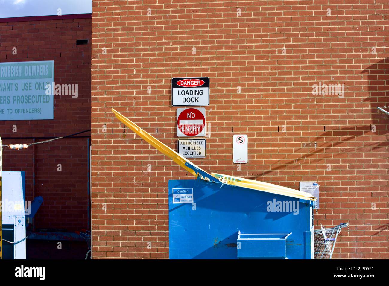 A danger loading dock sign and a no entry sign on a brick ball near a ...