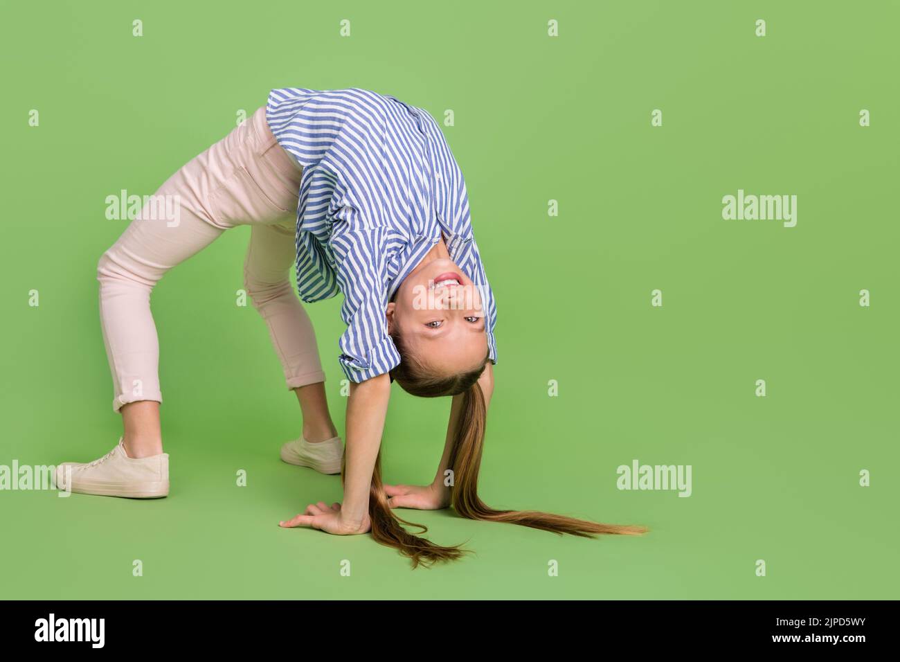 Photo of positive energetic kid girl wear striped shirt make bridge ...