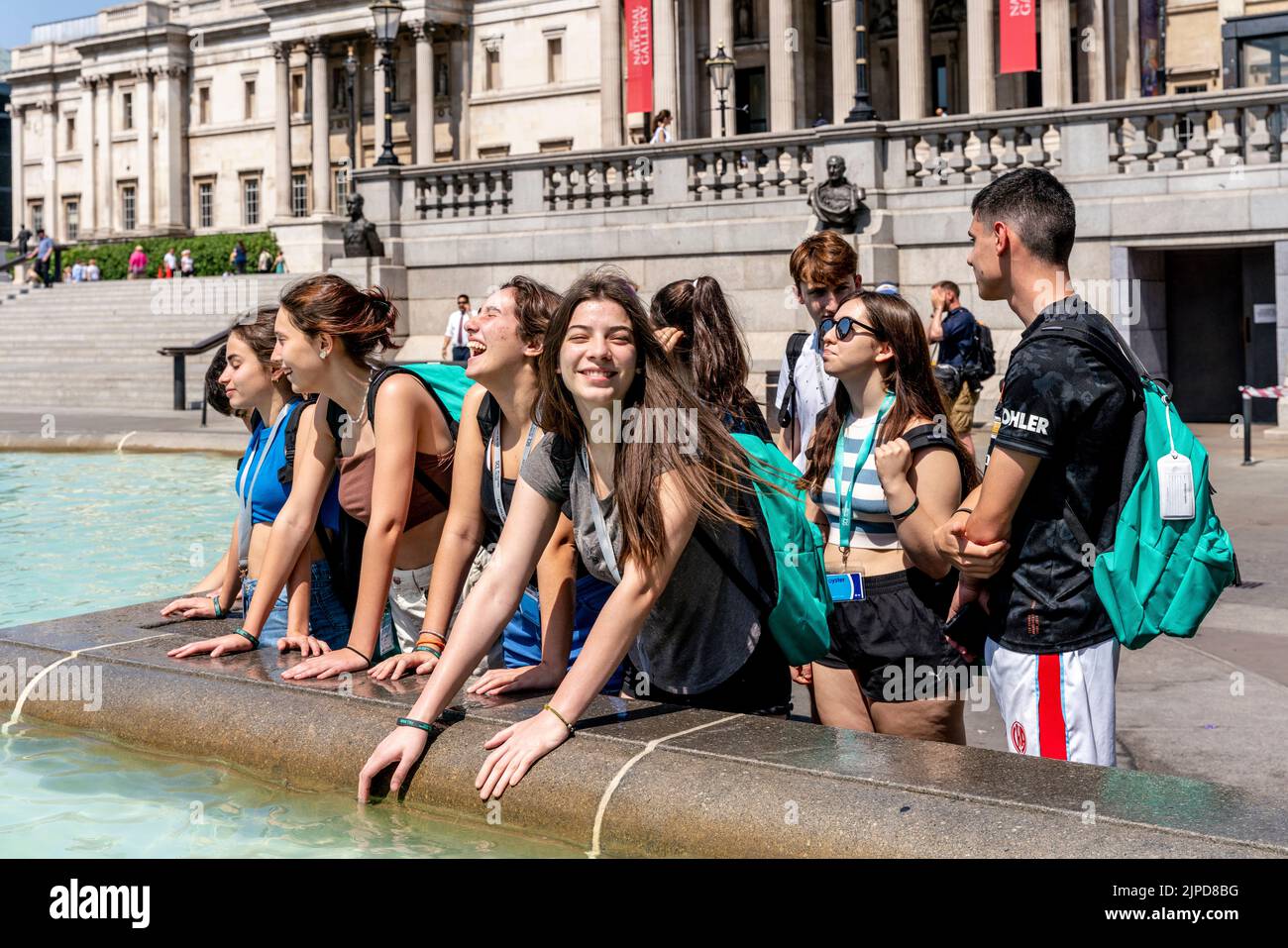 A Group Of Young Tourists Cool Down In The Spray Of The Fountains In Trafalgar Square On The ...