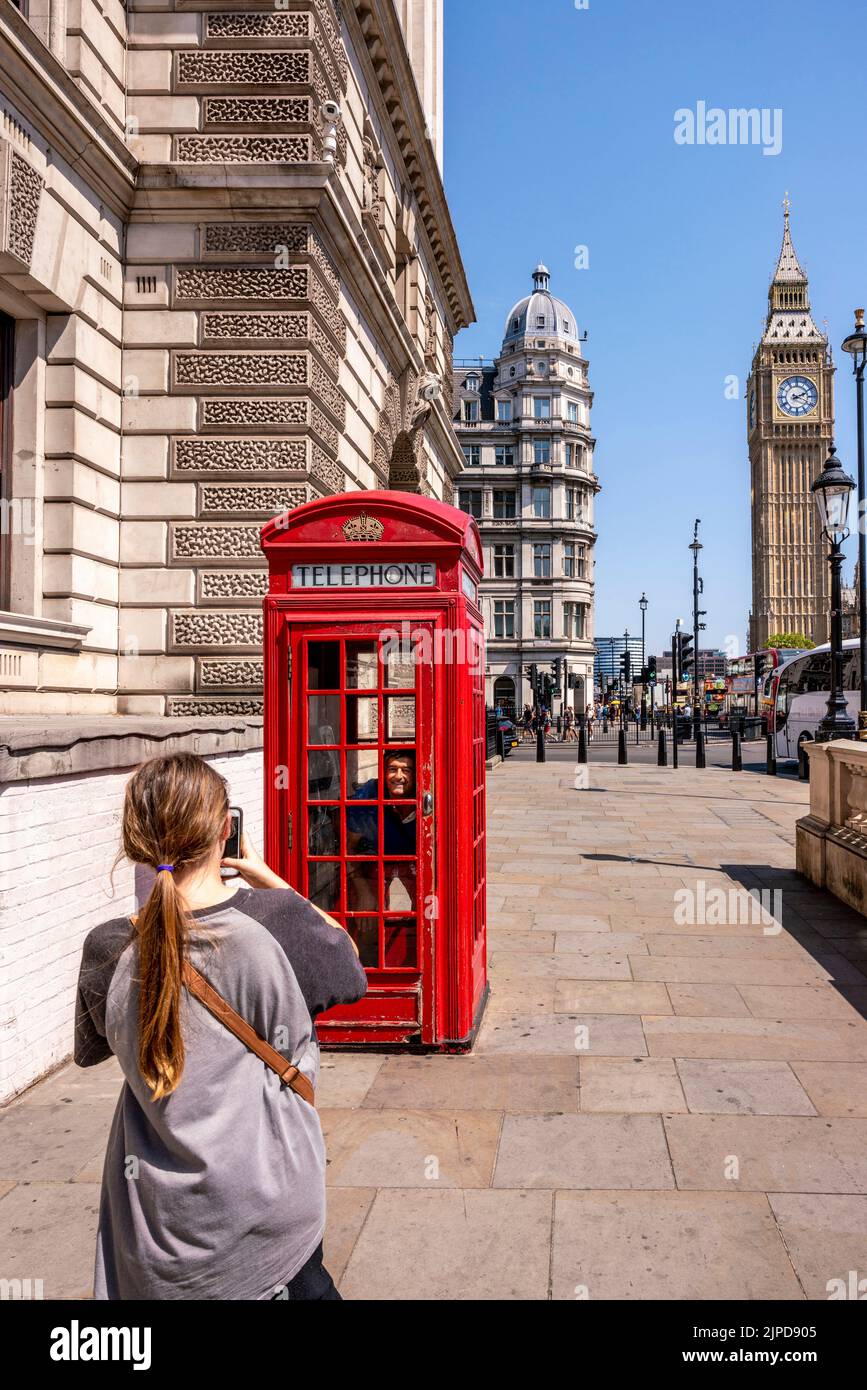 Tourists Pose For Photos Outside A Traditional Red Telephone Box In ...