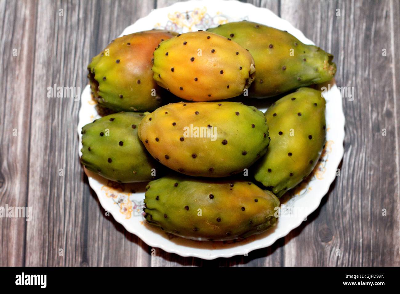 A plate with pile of fresh prickly pear fruit isolated on wooden ...