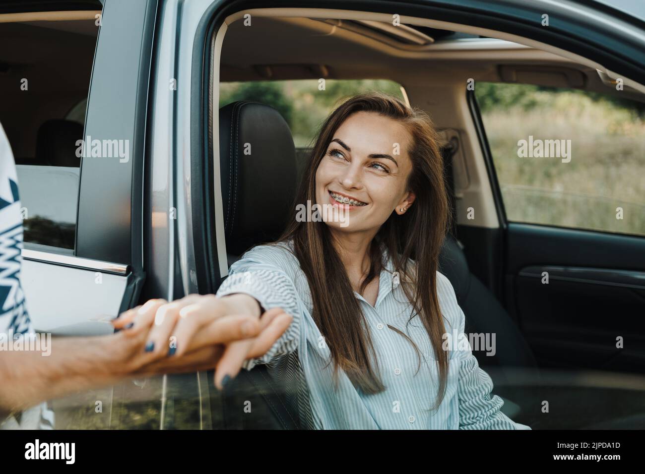 Man gives a hand to a beautiful middle-aged woman with braces system ...