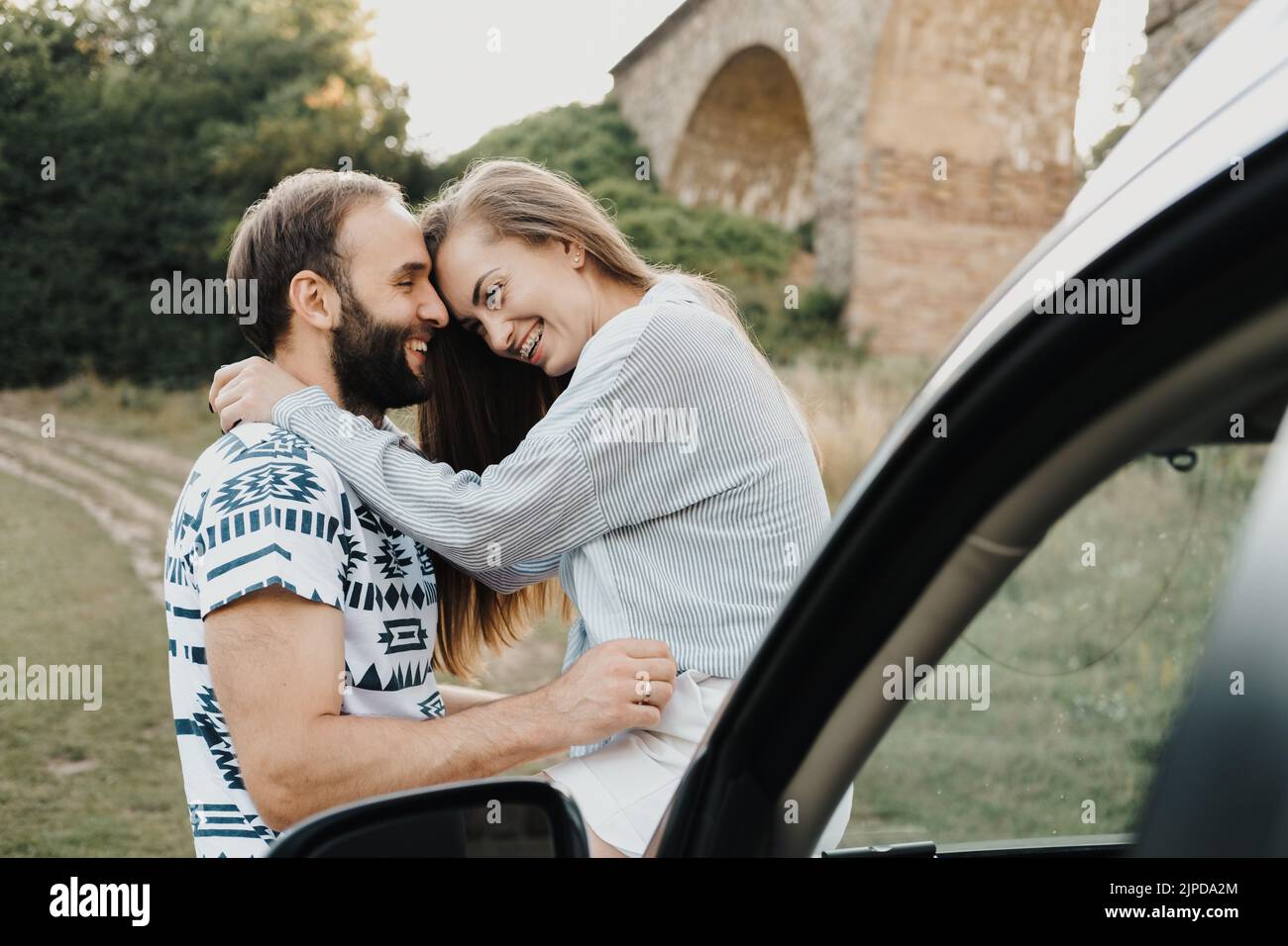 Caucasian man and woman hugging on the hood of car, middle-aged couple ...