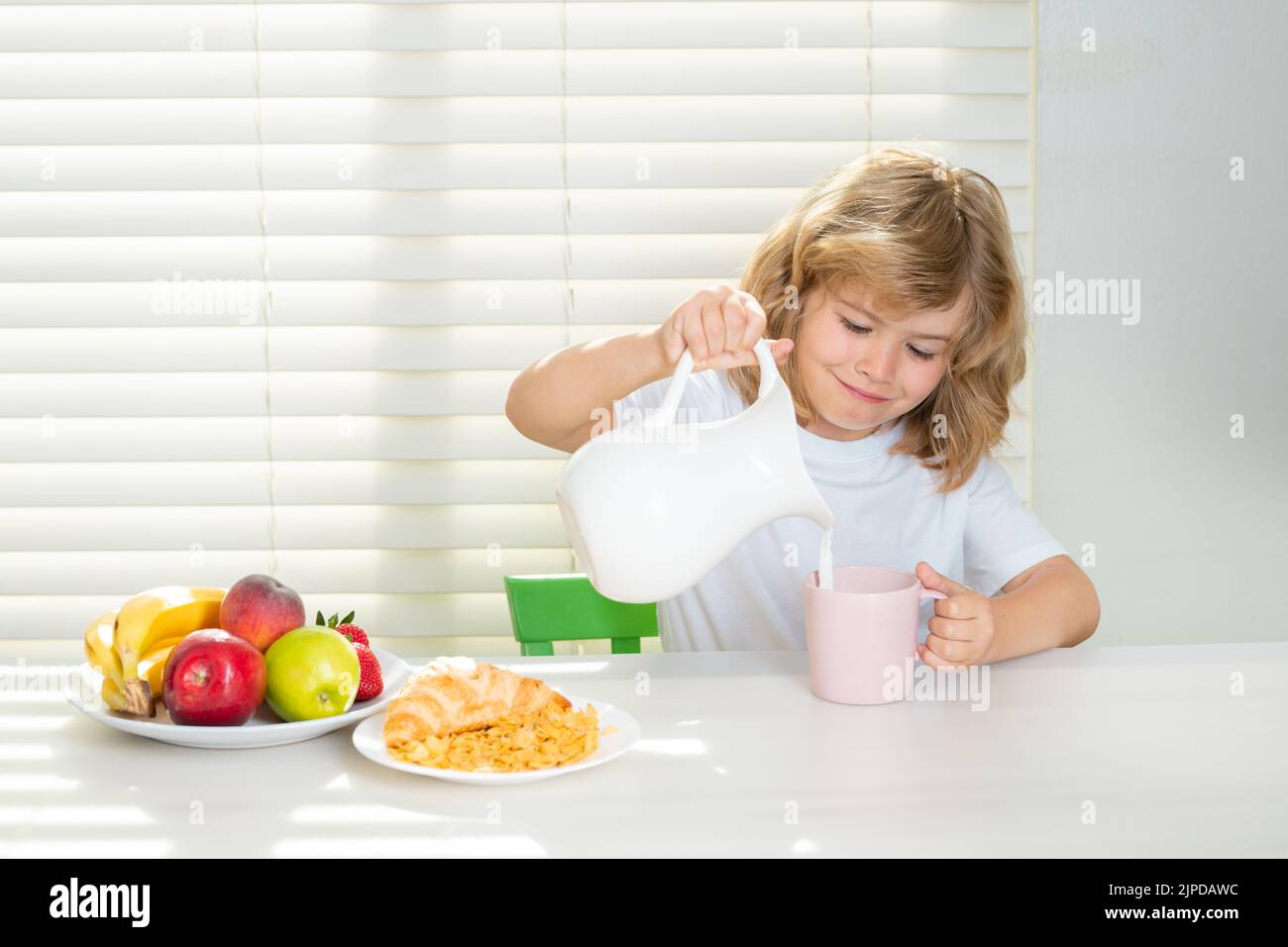 School chil pouring whole cows milk for breakfast. Child in the kitchen ...