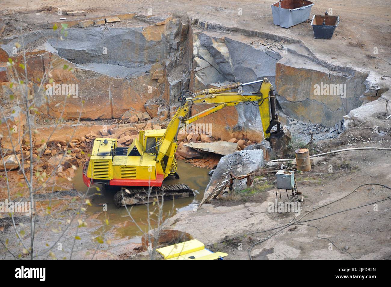 Old yellow rusty excavator digging stones and ground in the granite ...