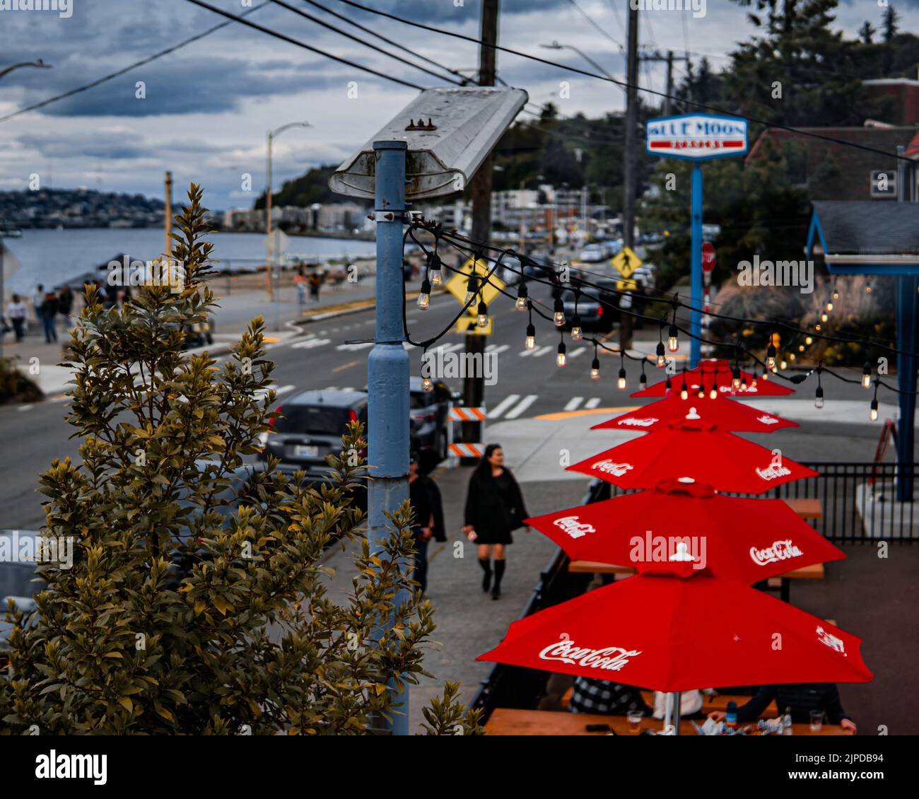 A high angle of people walking on a street next to an outdoor cafe with ...