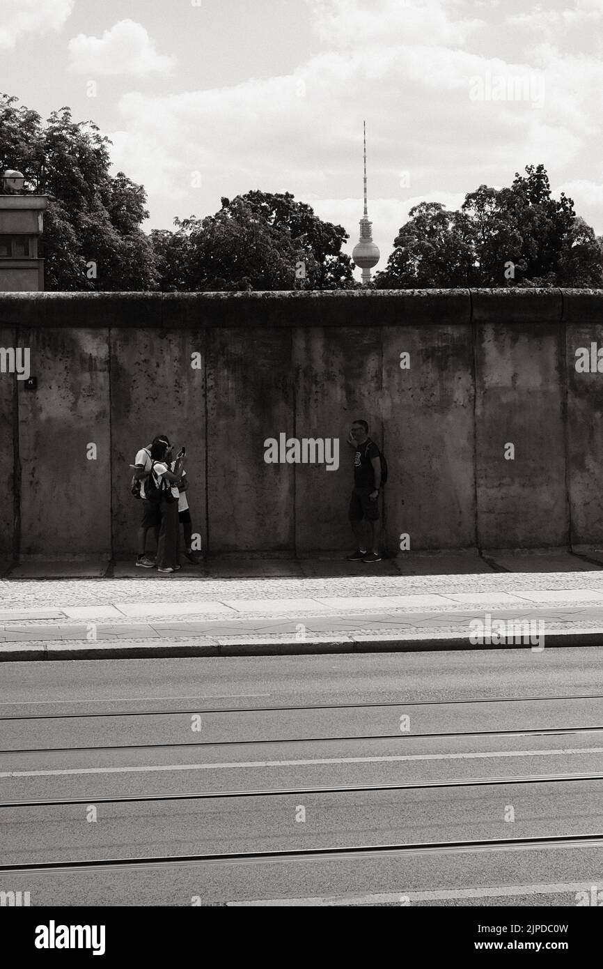 A vertical shot of people in front of the old Berlin Wall with Berlin ...