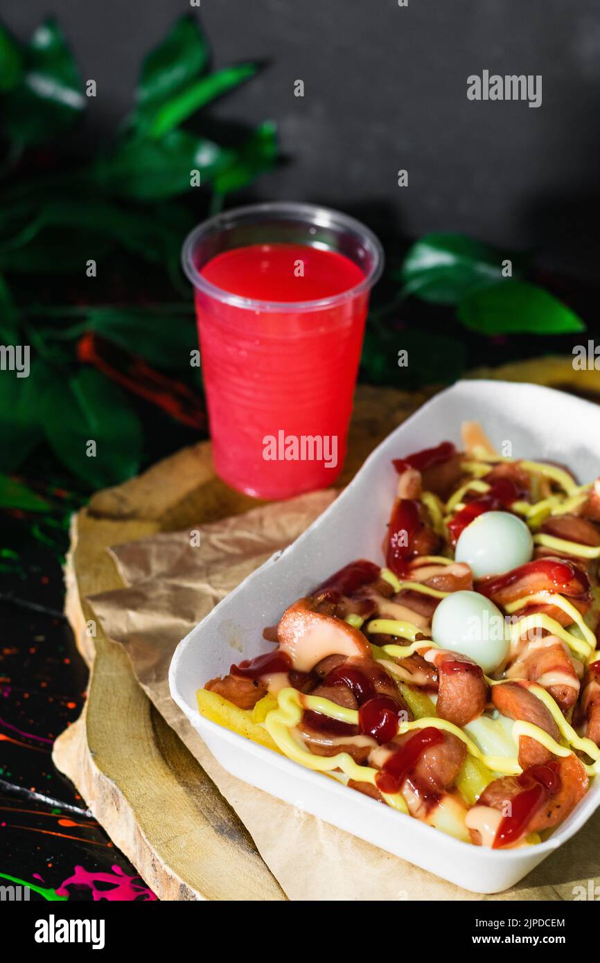 colombian street food, salchipapa served on a wooden tray with a glass ...