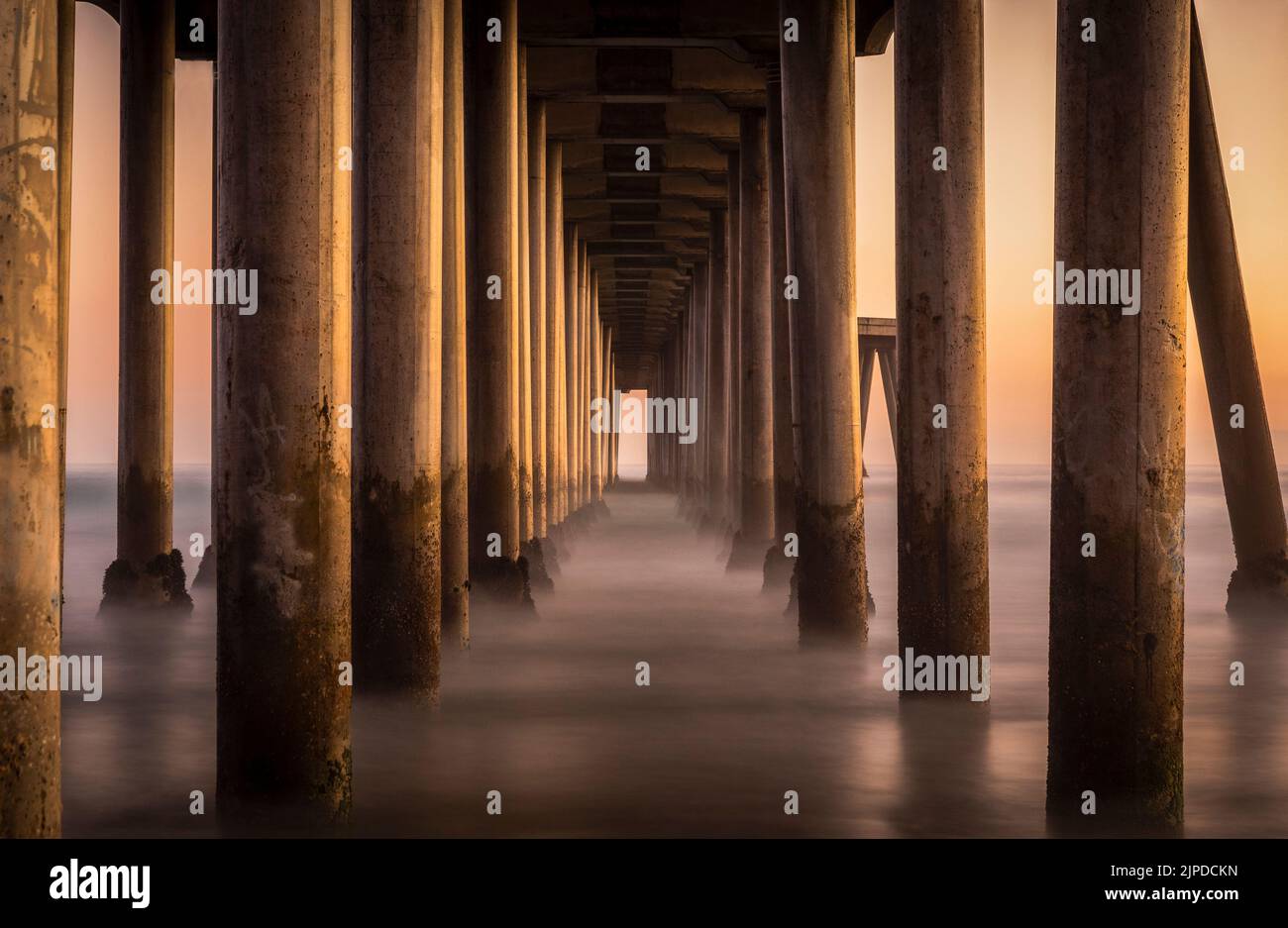 The landscape of pier with columns on Huntington Beach at golden sunset ...