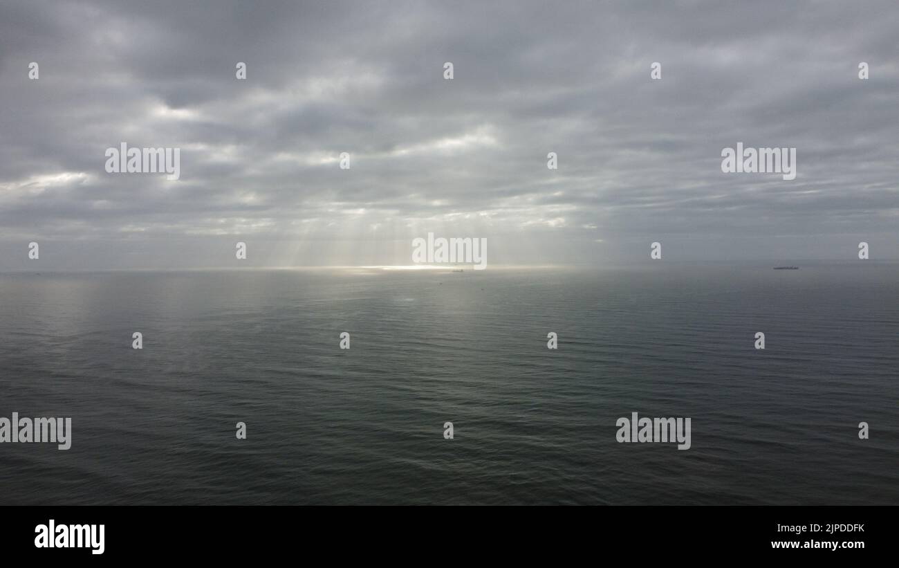 An aerial view of distant sun rays in the cloudy sky shining on the sea ...