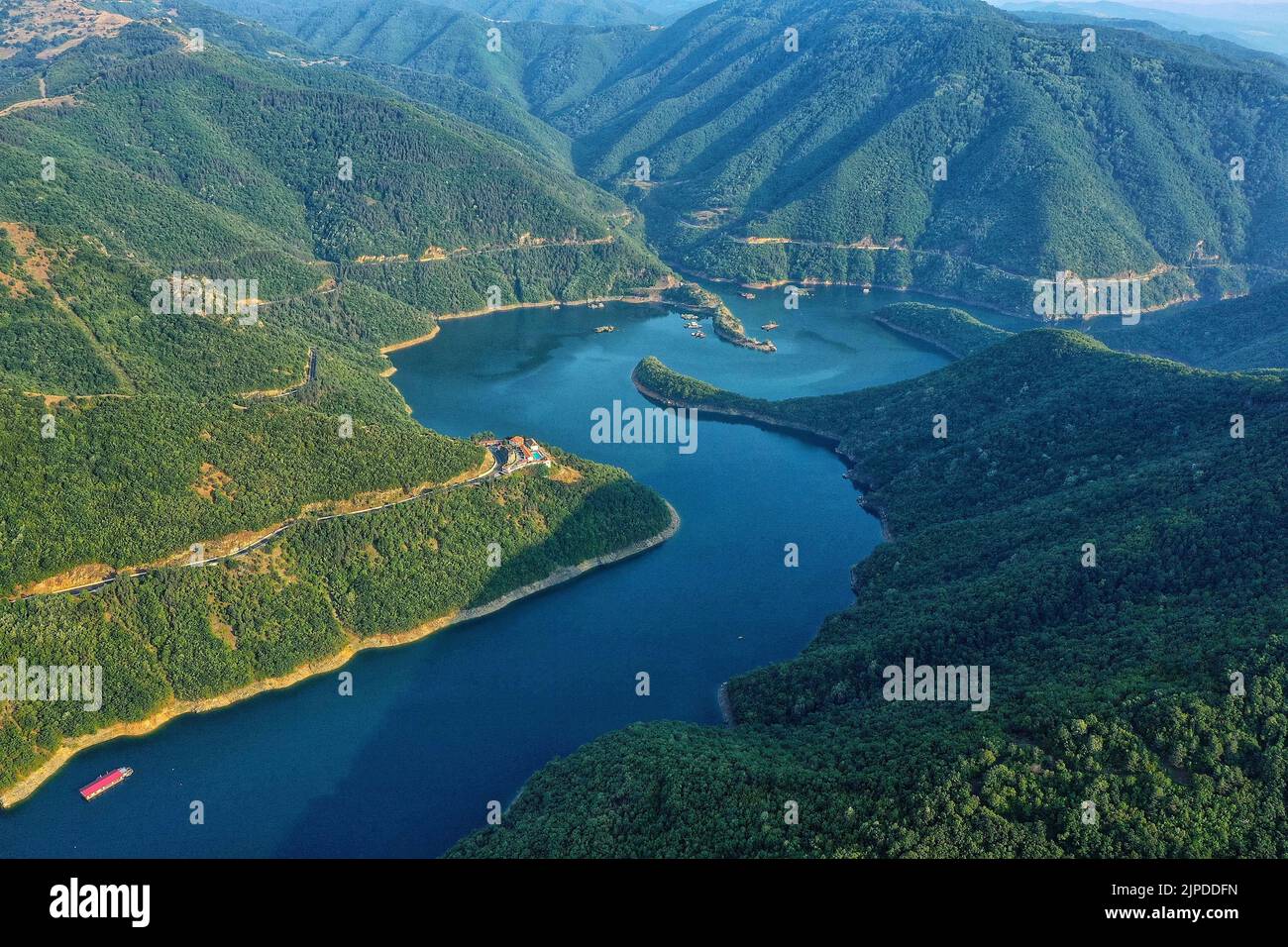 An aerial view of lake Piva surrounded by lush green mountain forests ...