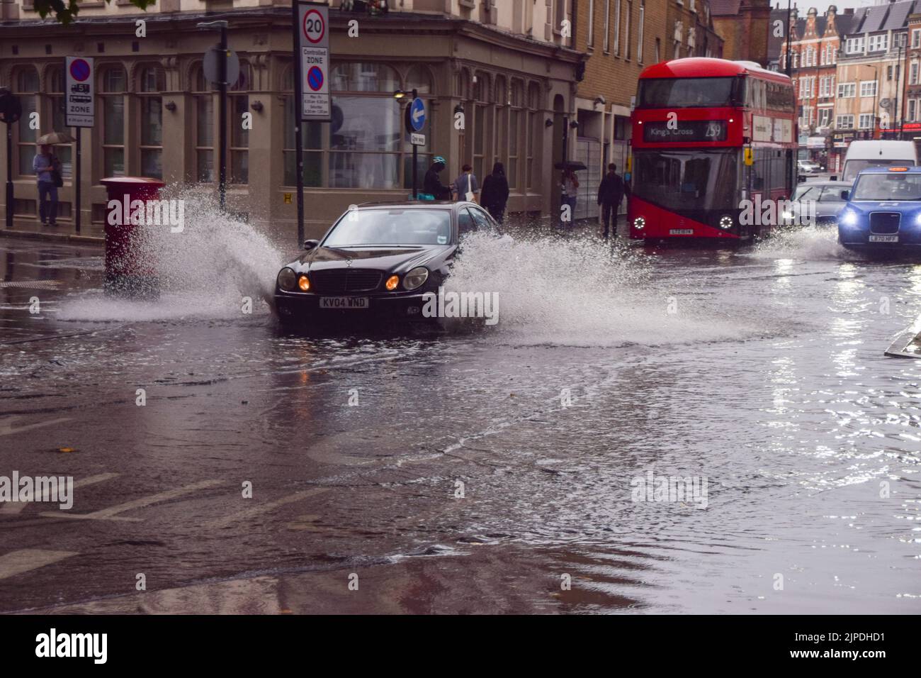 London, UK. 17th August 2022. A car splashes through a flooded King's ...