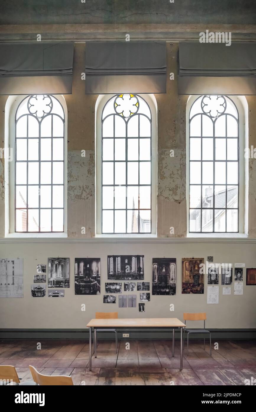 three large windows, with a desk and chair at the bottom, is an ...