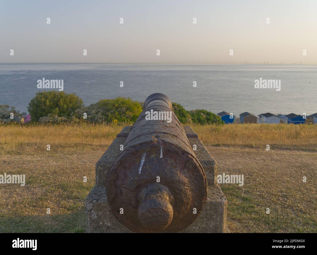 Old Rusty cannon on the hill over looking sea beach and beach huts ...