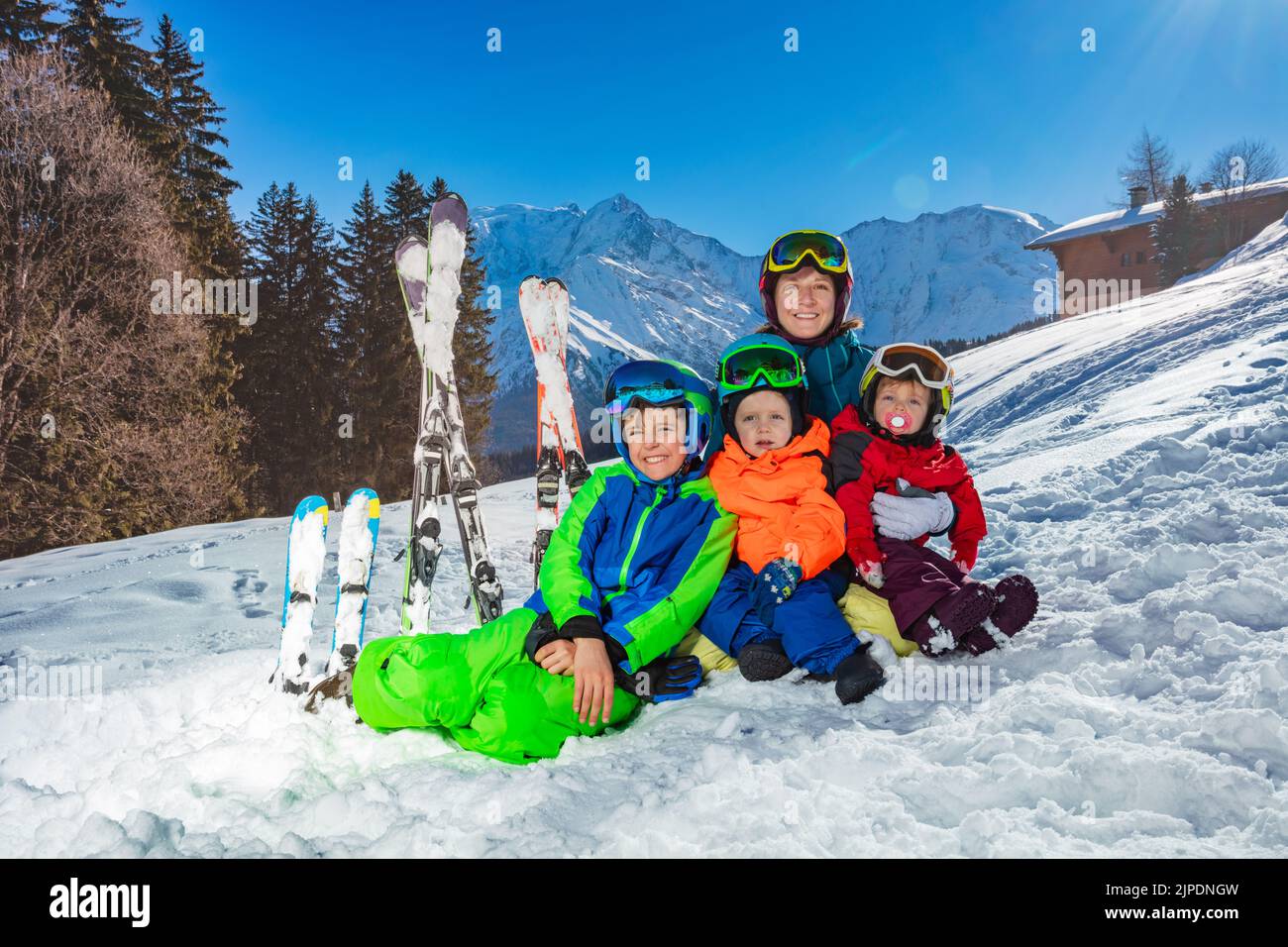Three kids with mother sit in snow over ski and Alps mountains Stock ...
