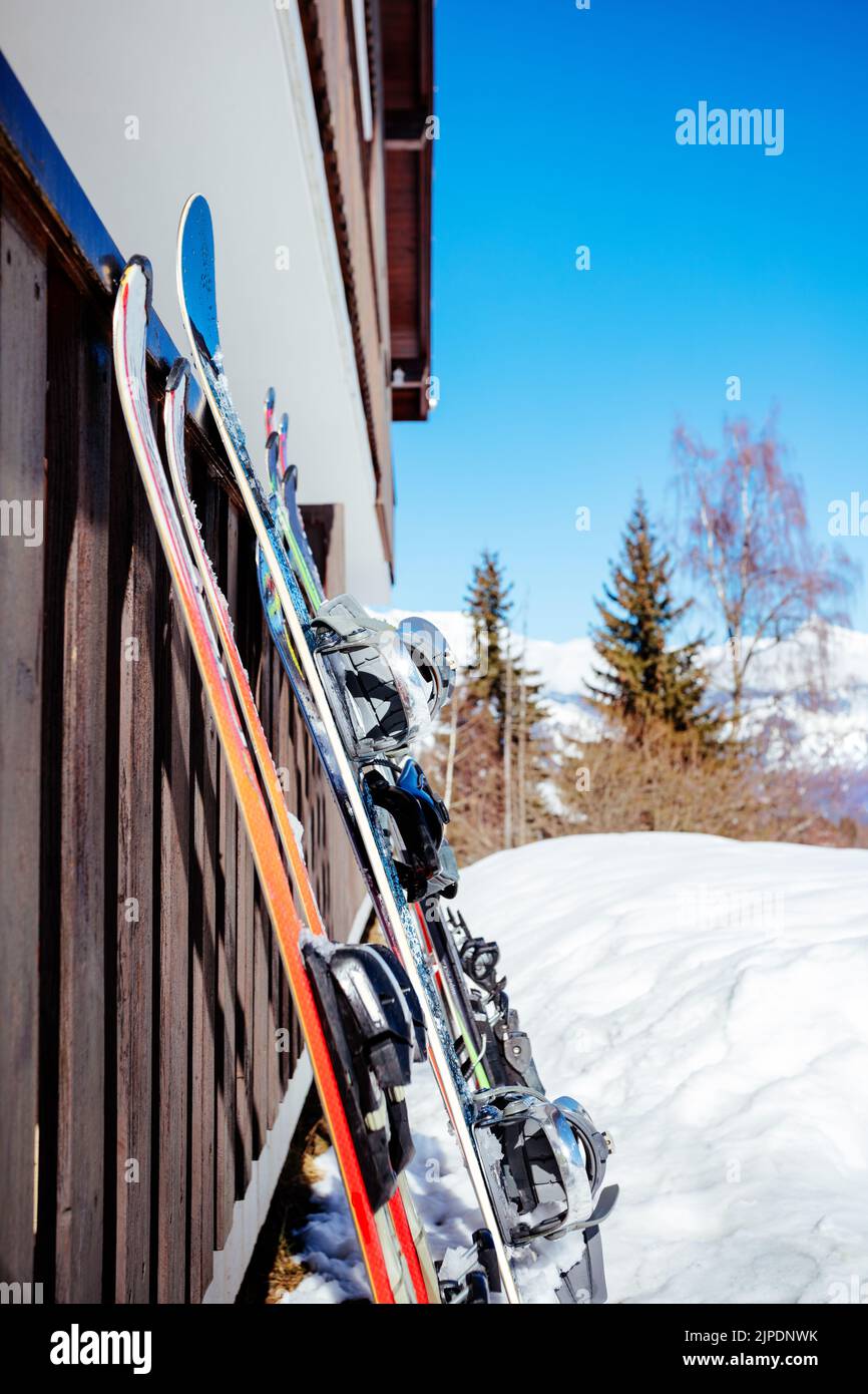 Skis and snowboard stand on alpine resort near building Stock Photo - Alamy