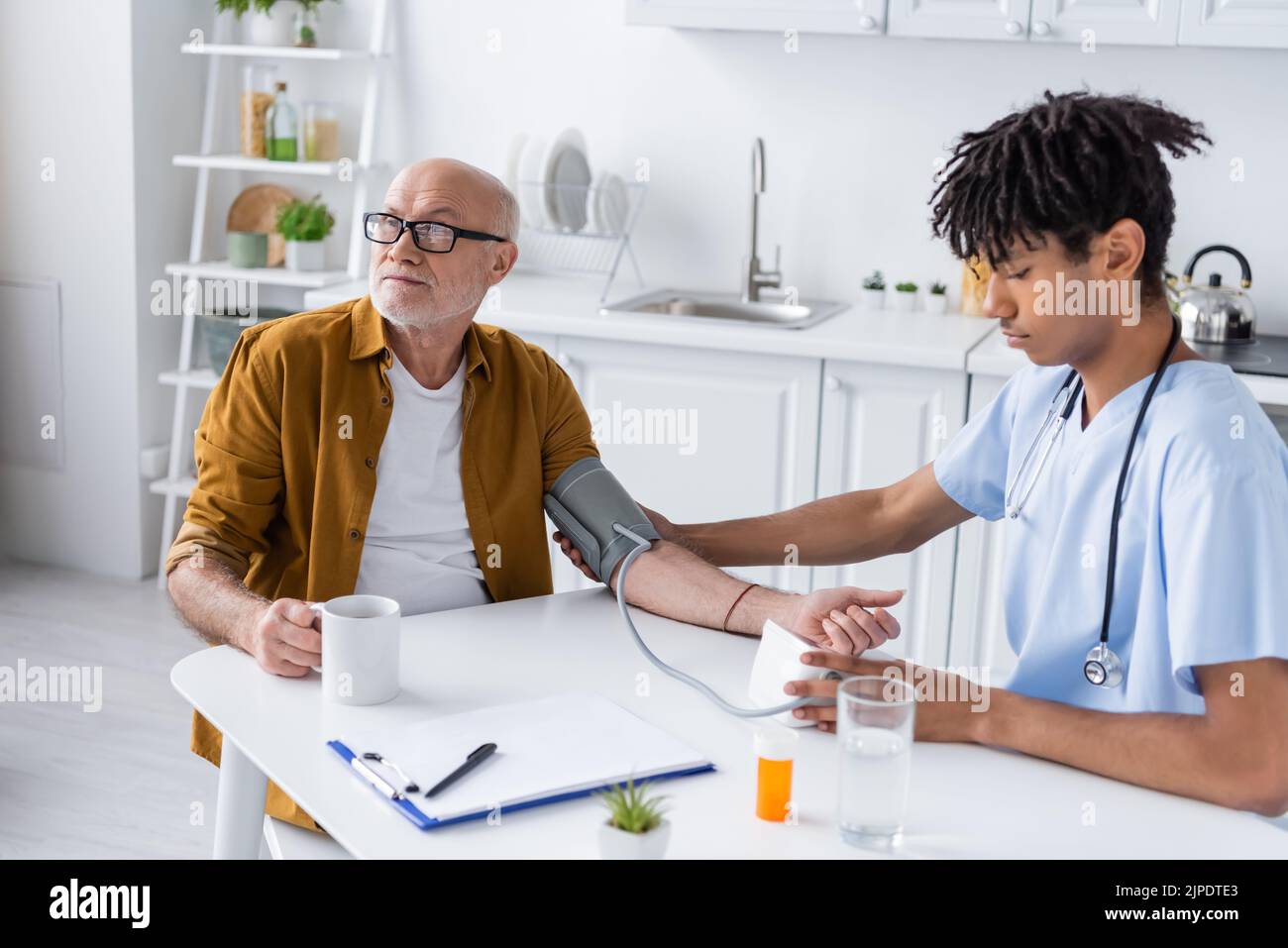 African american nurse checking blood pressure of elderly patient at ...