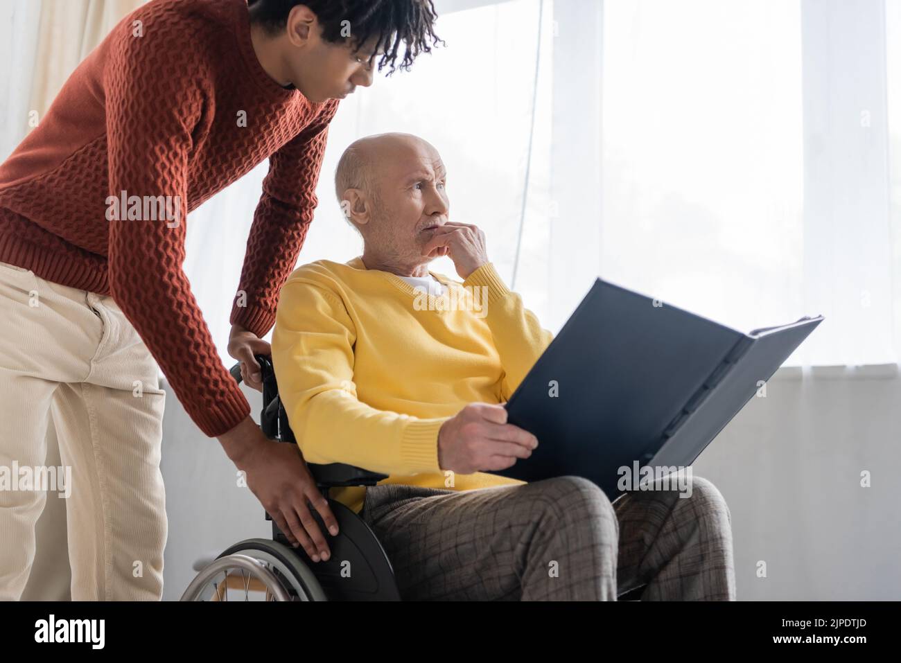 African american grandson looking at sad grandpa holding photo album in ...