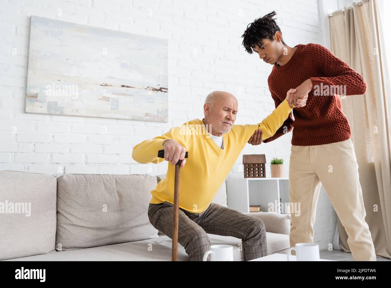 African american grandson helping displeased granddad with walking cane ...