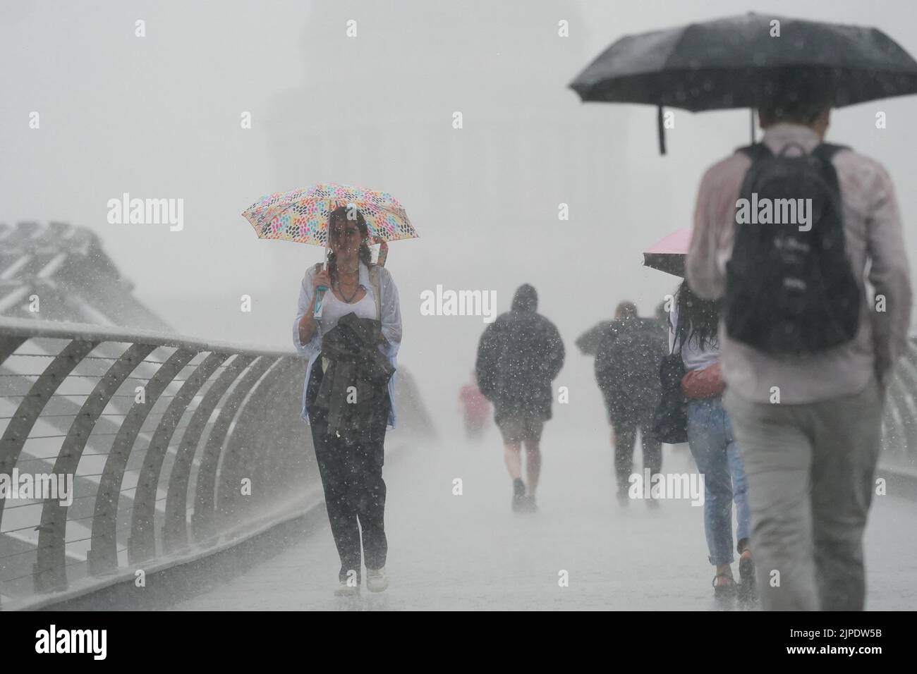 People with umbrellas walking in the rain on Millennium Bridge, London ...