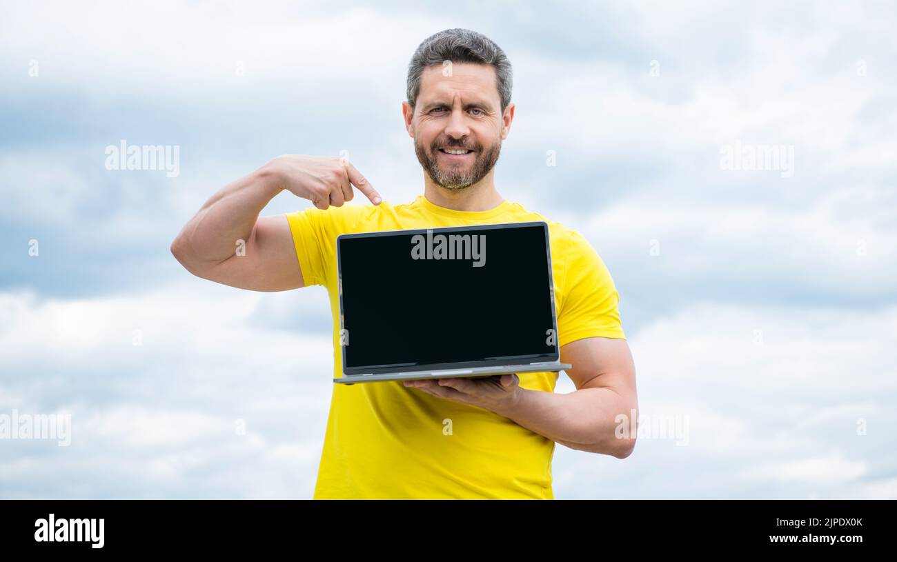 man presenting computer on sky background. copy space Stock Photo - Alamy
