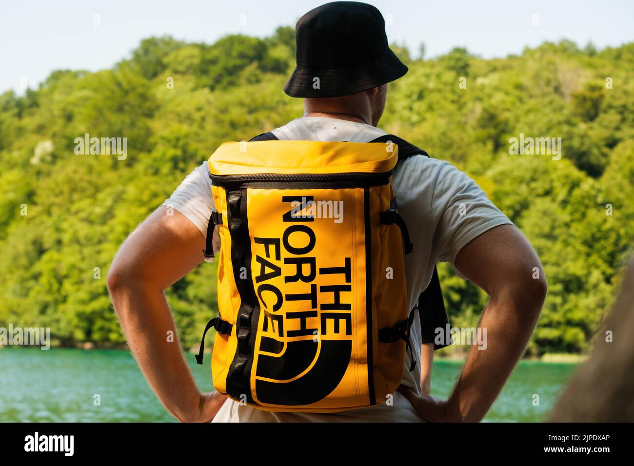 Tourist with yellow The North Face backpack standing near the lake ...
