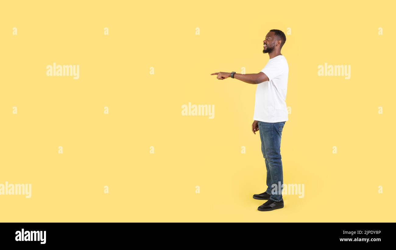 African Man Pointing Finger Aside At Empty Space, Yellow Background ...