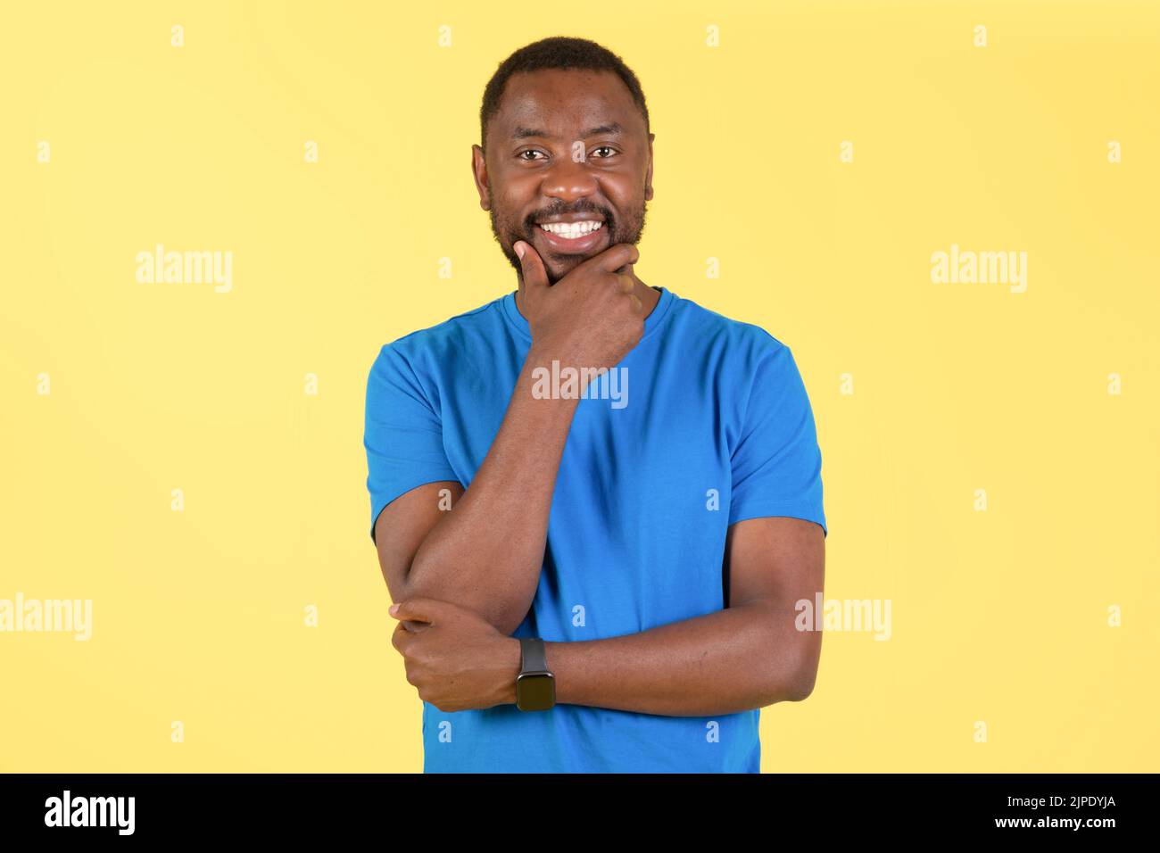 Black Male Posing Touching Chin Smiling Over Yellow Studio Background Stock Photo - Alamy