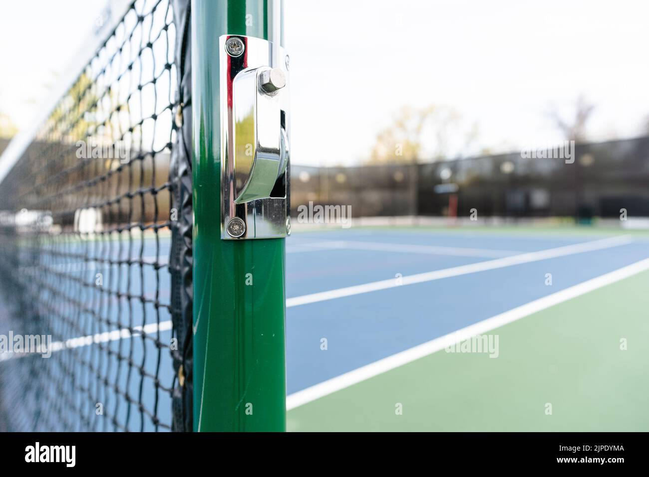 Photo of a new green tennis court net post, blue tennis courts with ...