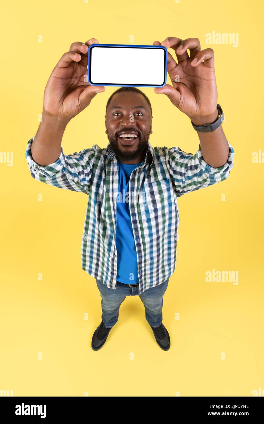 African American Male With Smartphone Showing Screen, Yellow Background ...