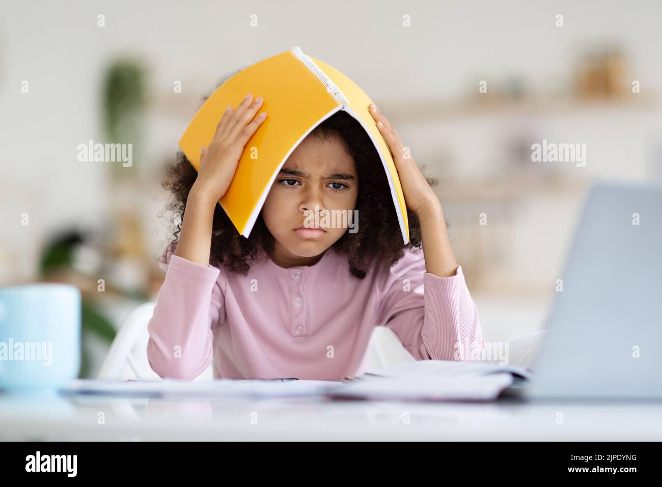 Angry african american schooler with notepad on her head Stock Photo ...